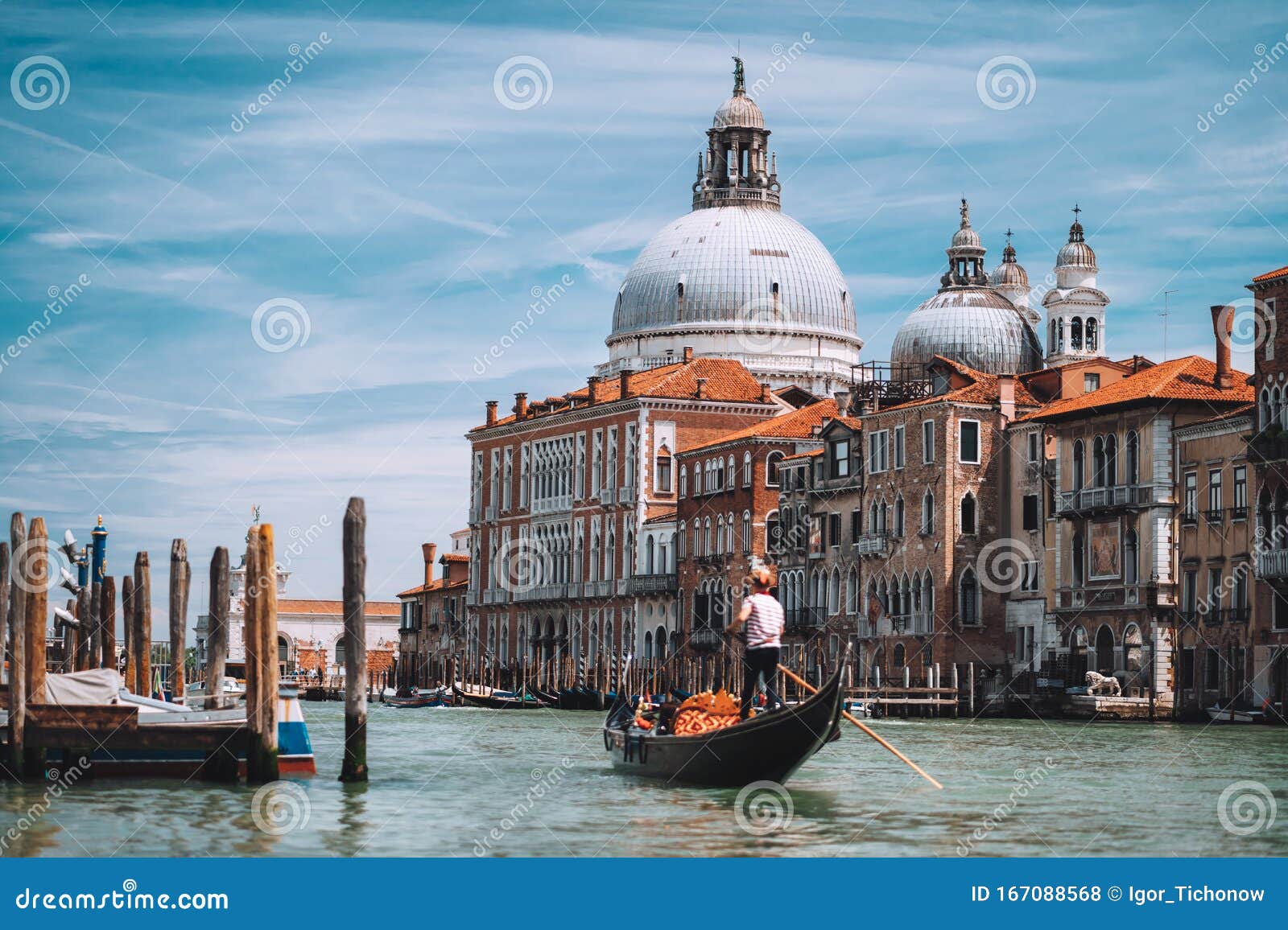 Traditional Gondola And Gondolier On Canal Grande With Basilica Di
