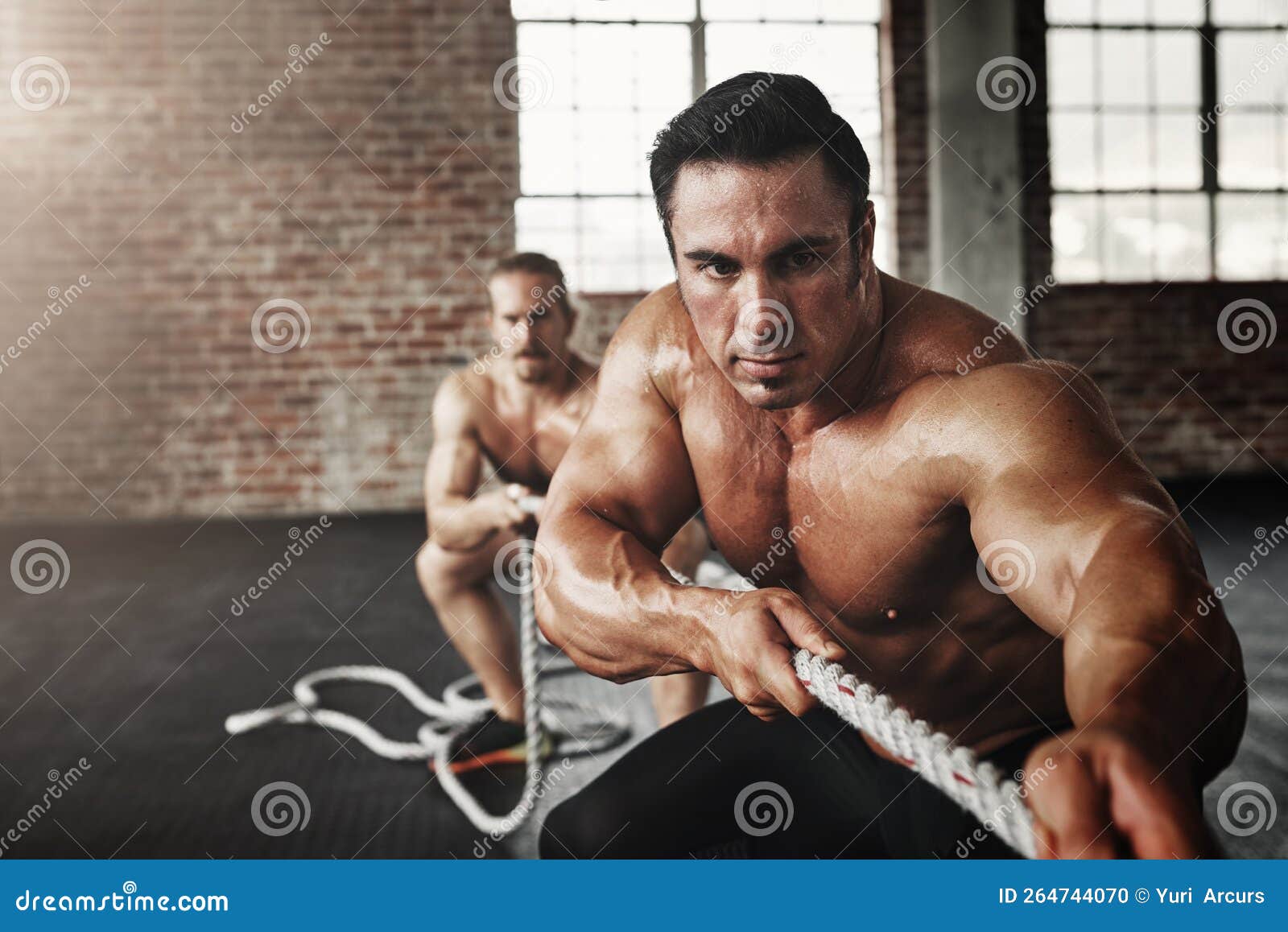 We Train Often and Hard. Two Muscular Young Men Pulling on a Rope in a ...