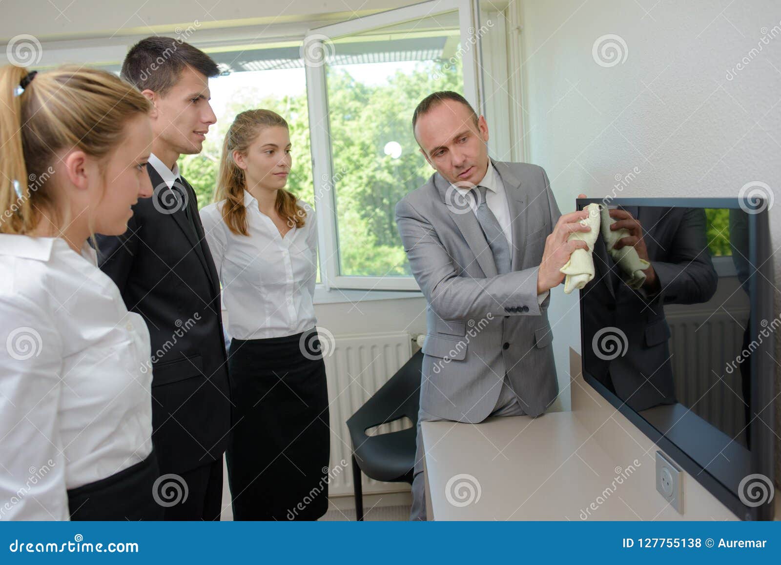 Trainee Cleaners Watching Supervisor Clean Television Screen Stock ...
