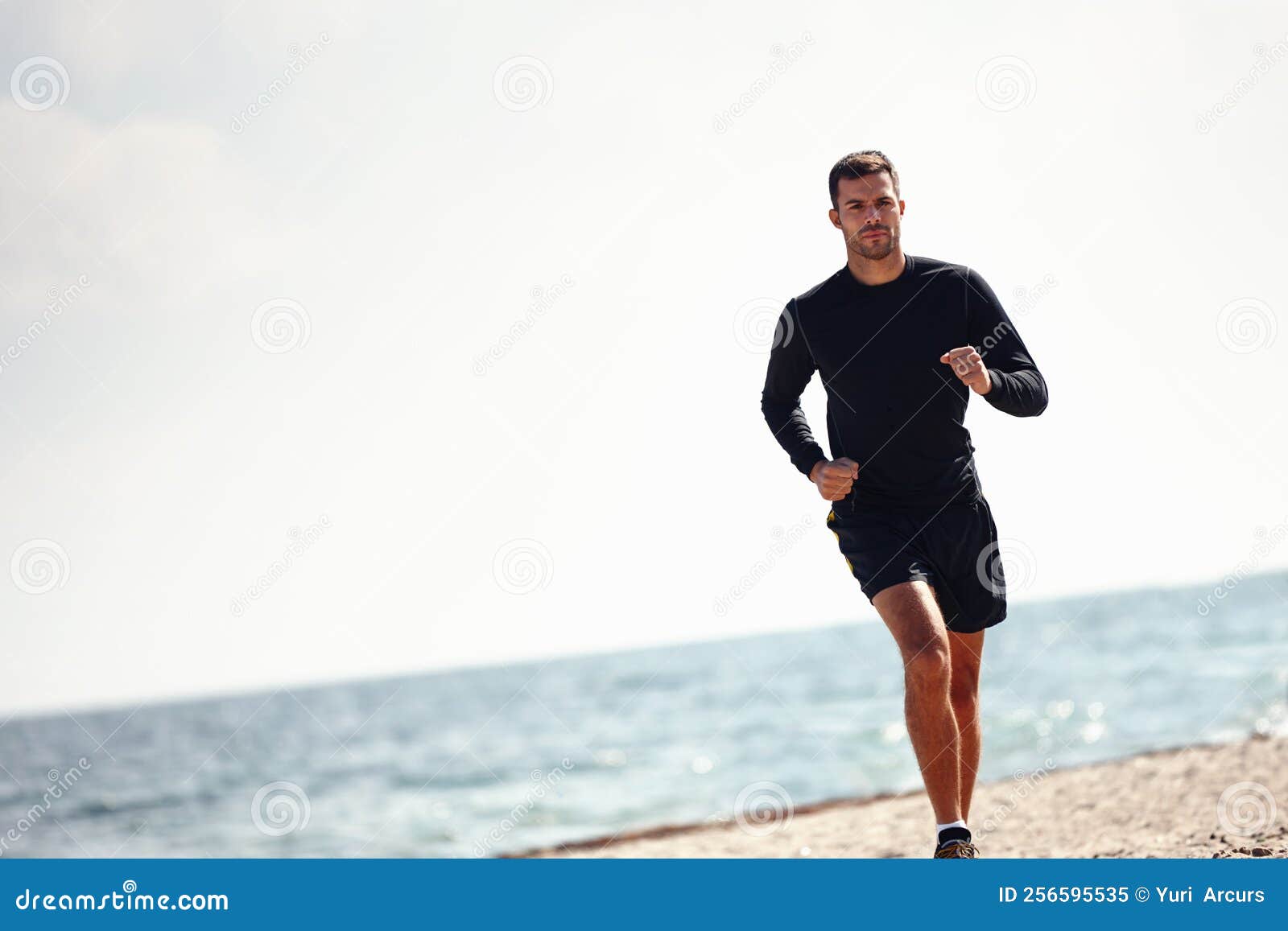 Training for a Big Run. a Handsome Young Man Running on the Beach ...