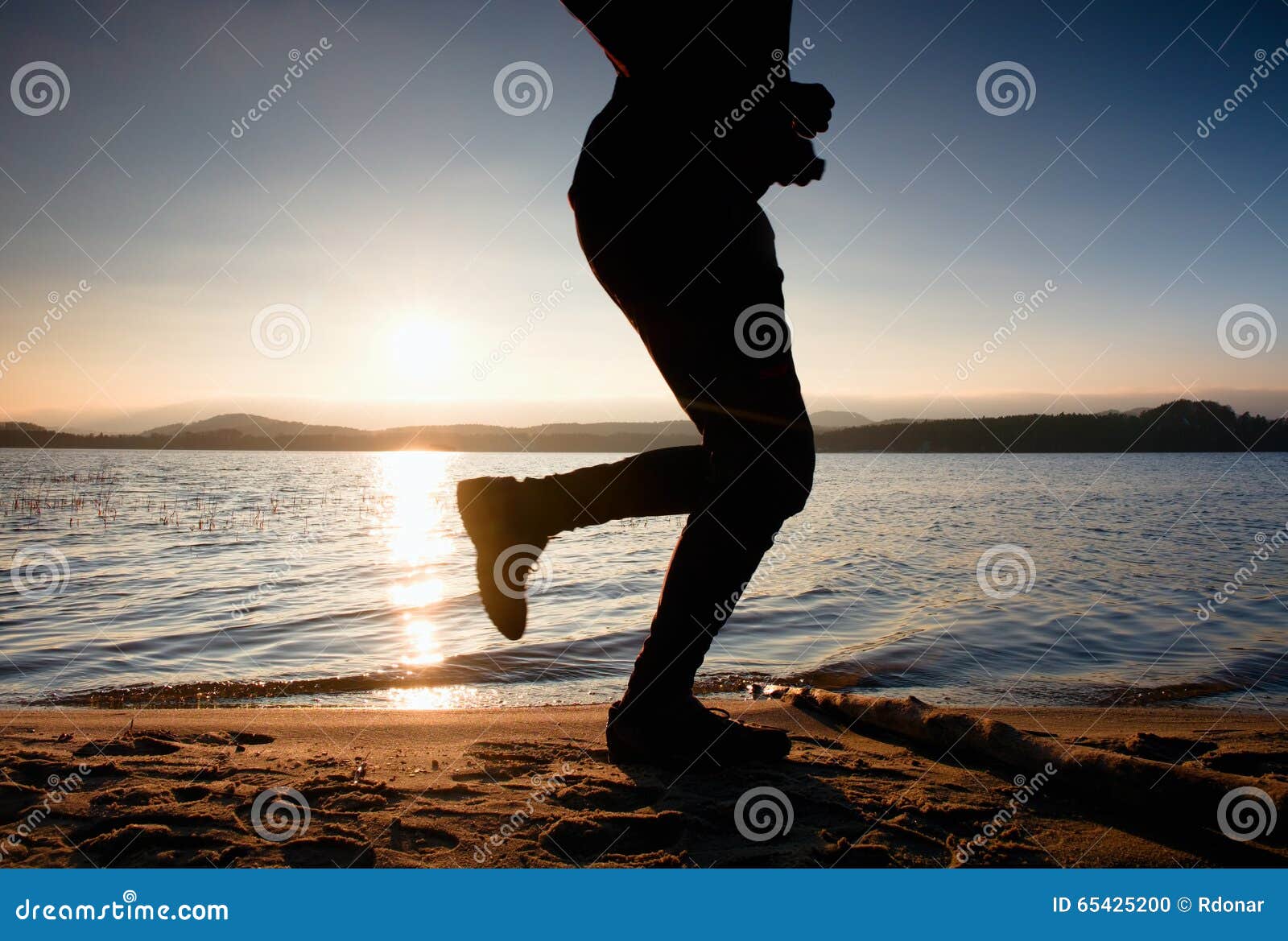 Training at Sunset. a Silhouette of Jogger at Path Along Lake Coastline ...