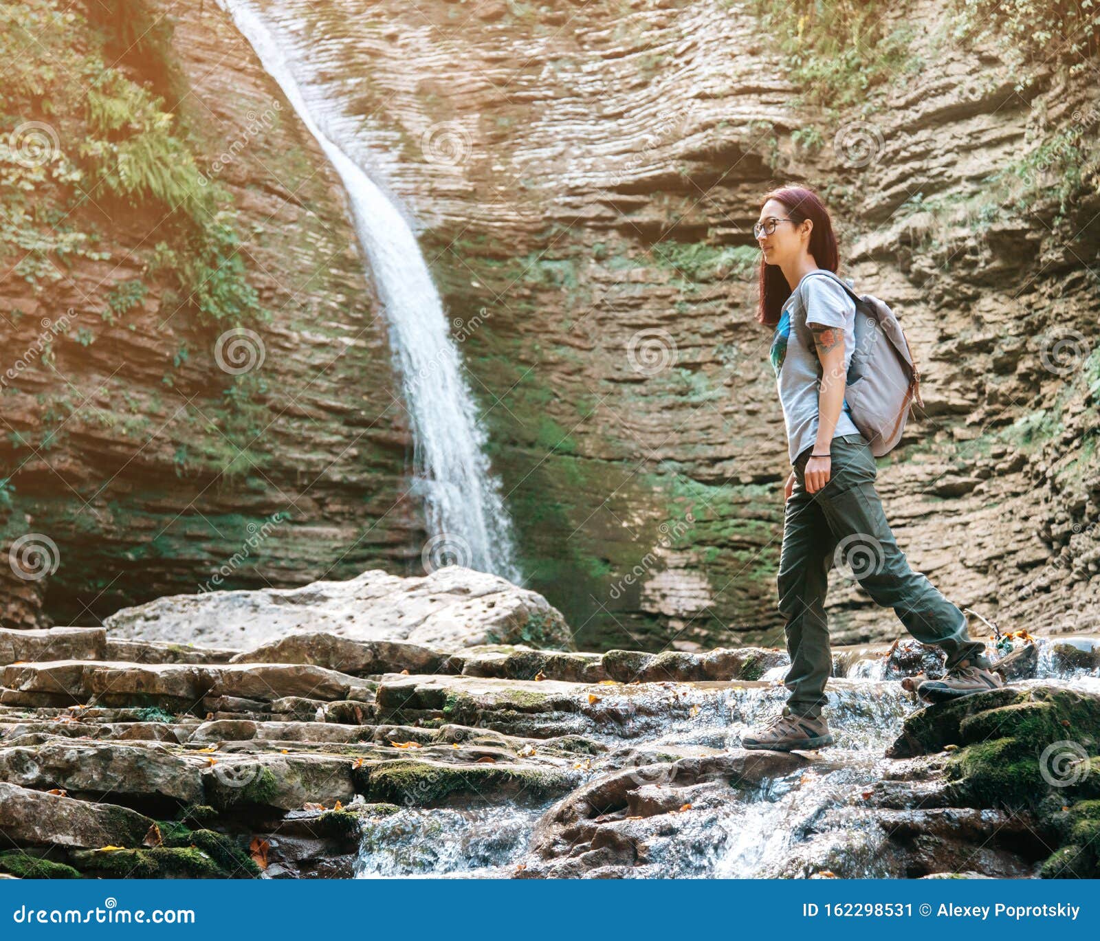 Traveler Woman Crossing River in Front of Waterfall. Stock Image ...