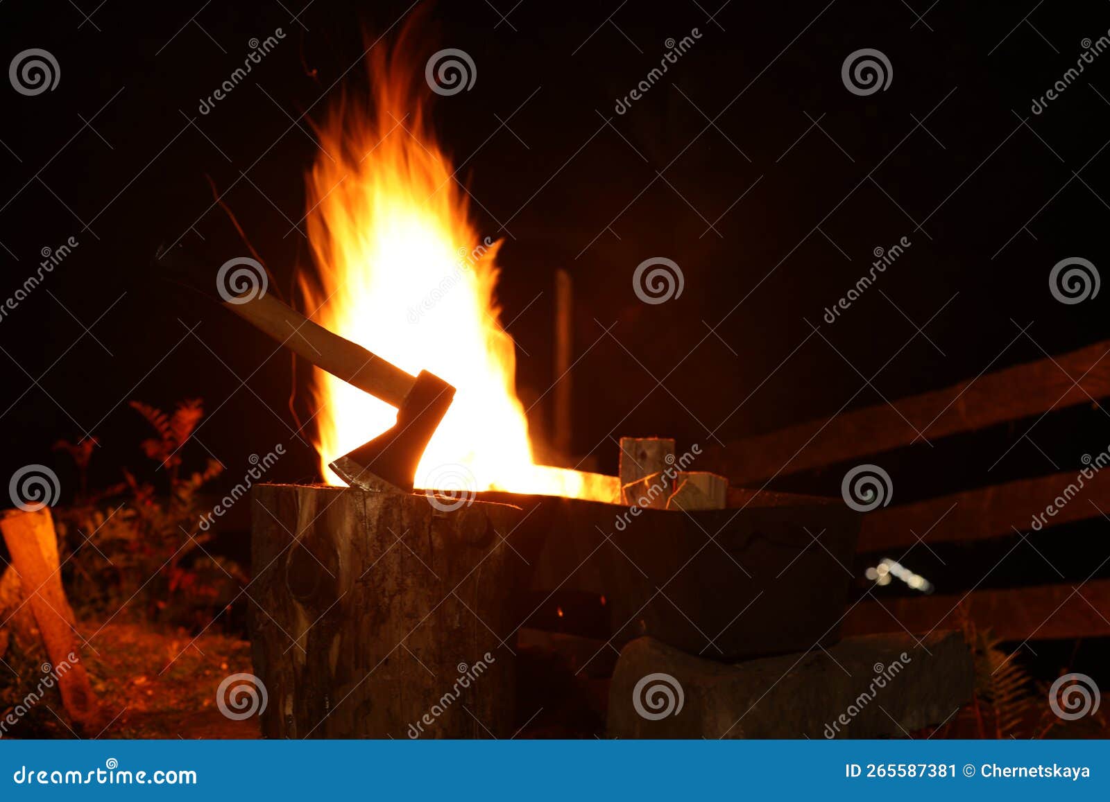 Tree Stump with Axe and Burning Firewood in Metal Brazier Outdoors at ...