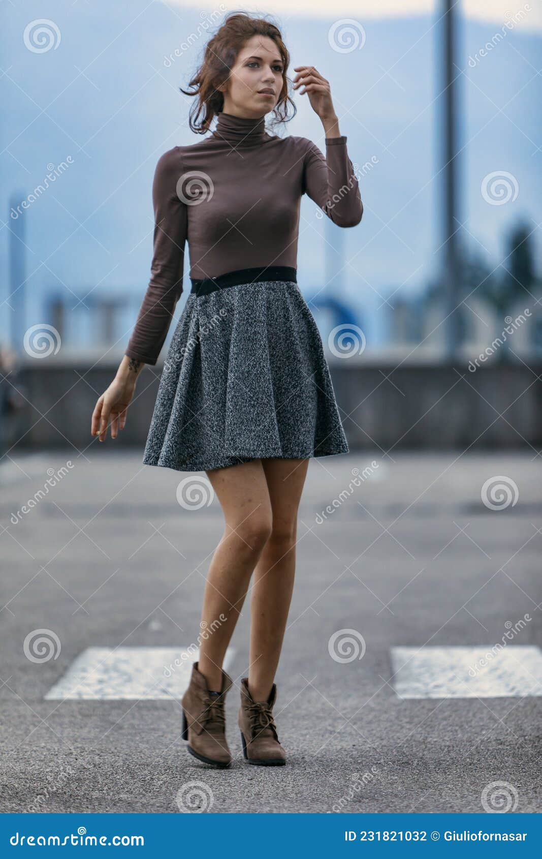 Trendy Young Woman In A Miniskirt Smoking As She Crosses Street Stock