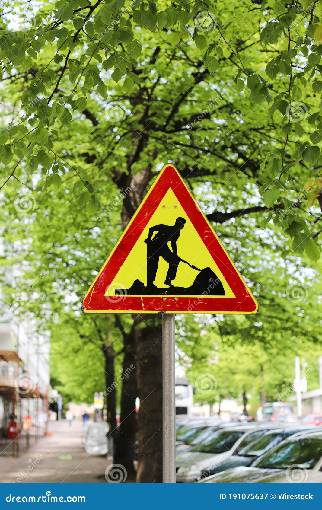 Triangle Road Construction Sign on a Post at a Street with Trees Stock ...
