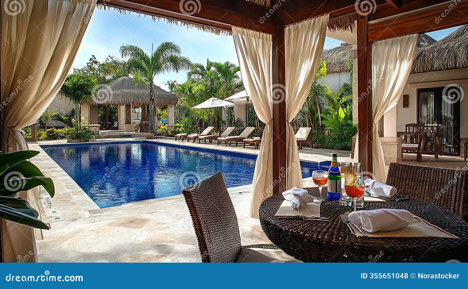 A Tropical Poolside Cabana with Curtains and a Table Set with Fresh ...