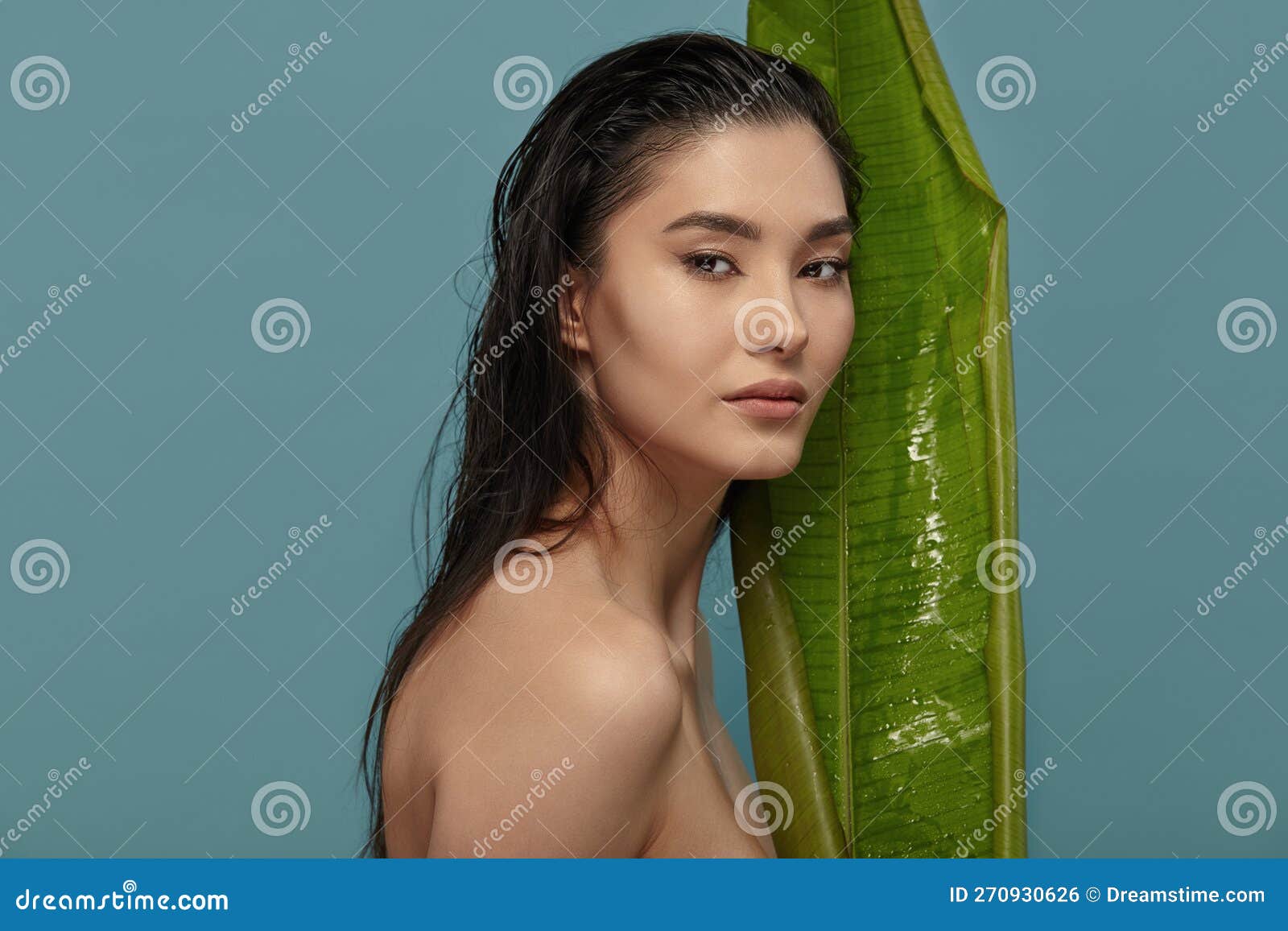 Tropical Woman Peeking Out From Behind Exotic Plant Big Leaf Stock