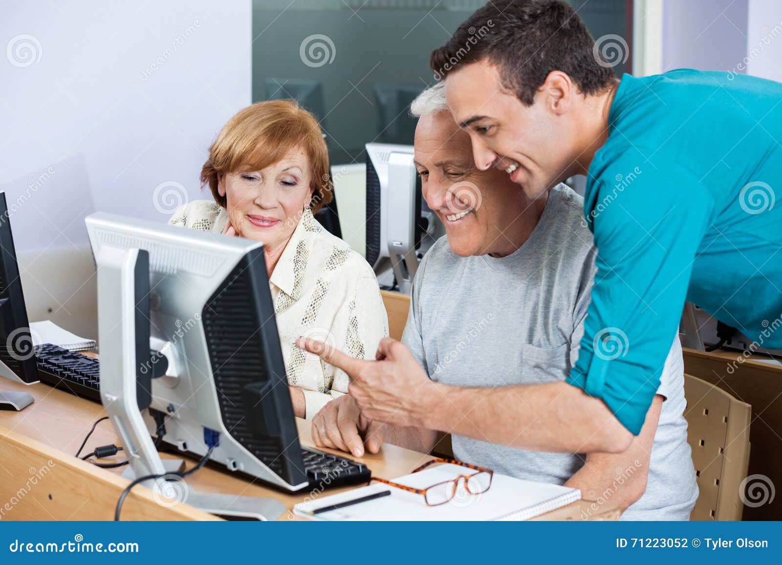 Tutor Assisting Senior Students in Using Computer at Class Stock Photo ...