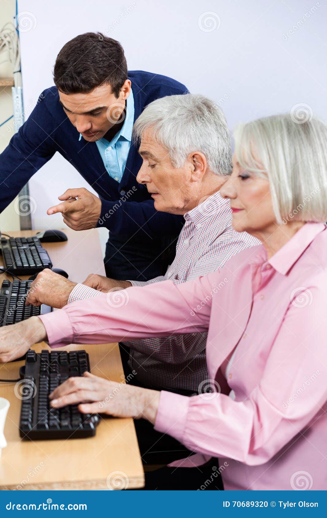 Tutor Explaining Senior Students Using Computers in Classroom Stock ...