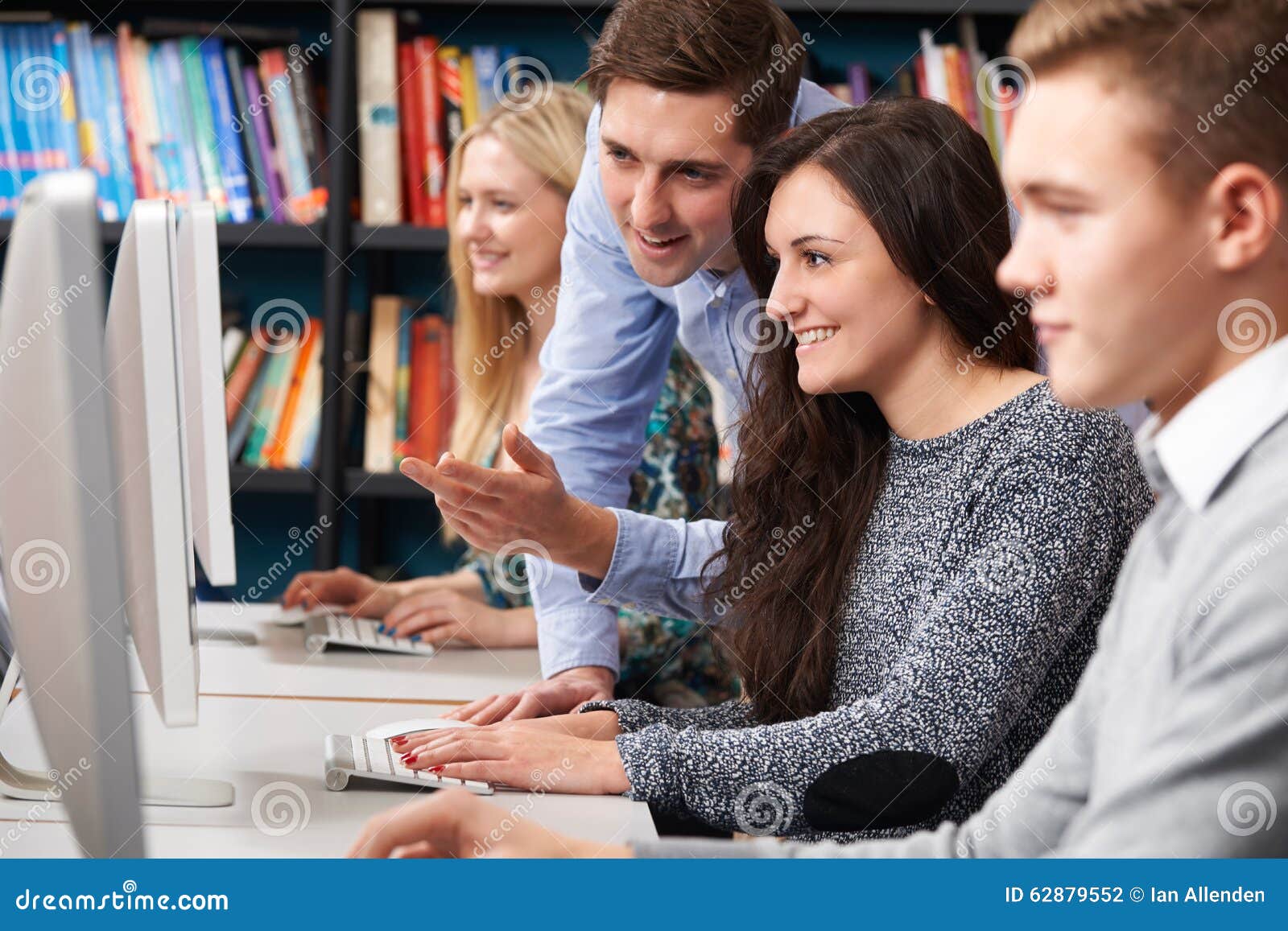 Tutor Helping Teenage Students Working at Computers Stock Photo - Image ...