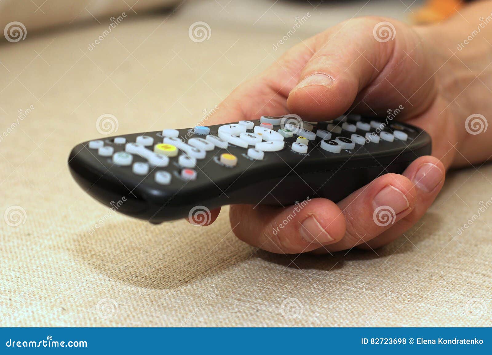 TV Remote Controller in the Man`s Hand on Light Textile Backgtround ...