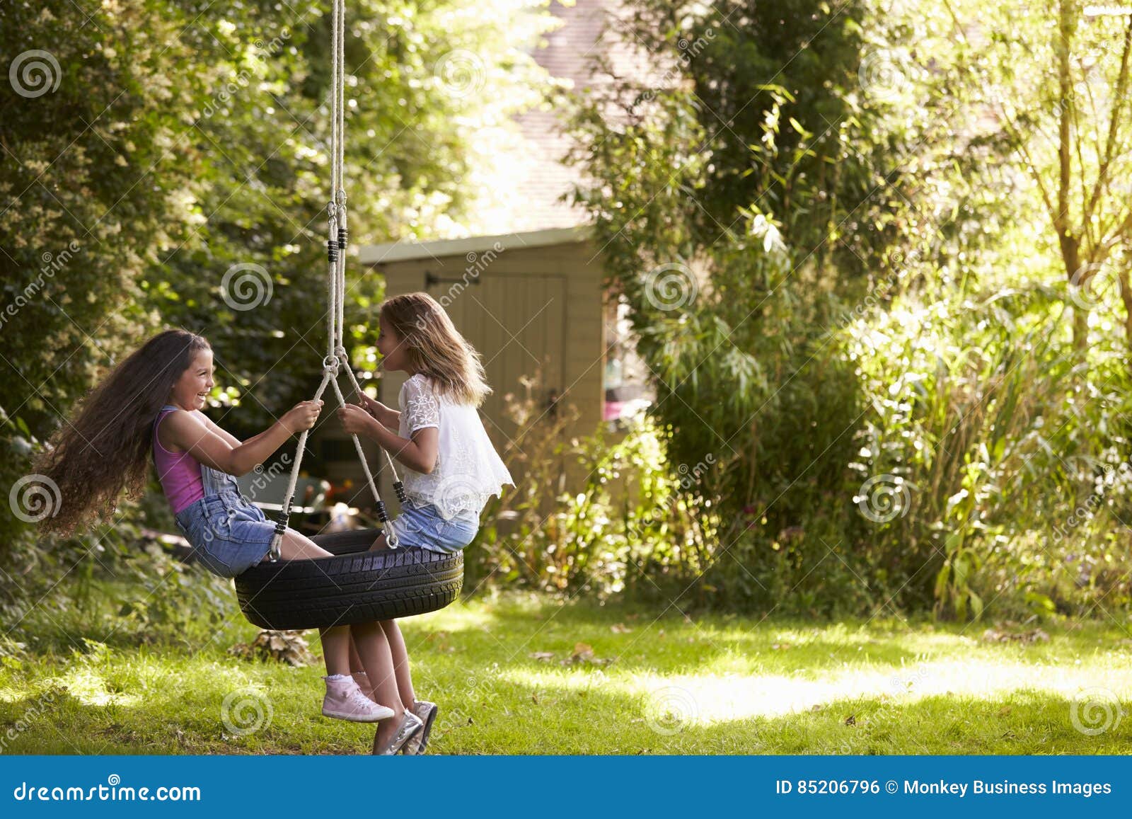 Twee Meisjes Die Samen Op Bandschommeling Spelen In Tuin Stock Foto