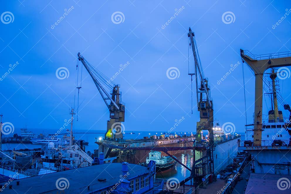 Twilight at Shipyard with Floating Dock, Vessels Undergoing Repair Amid ... Twilight at Shipyard with Floating Dock, Vessels Undergoing Repair Amid ...