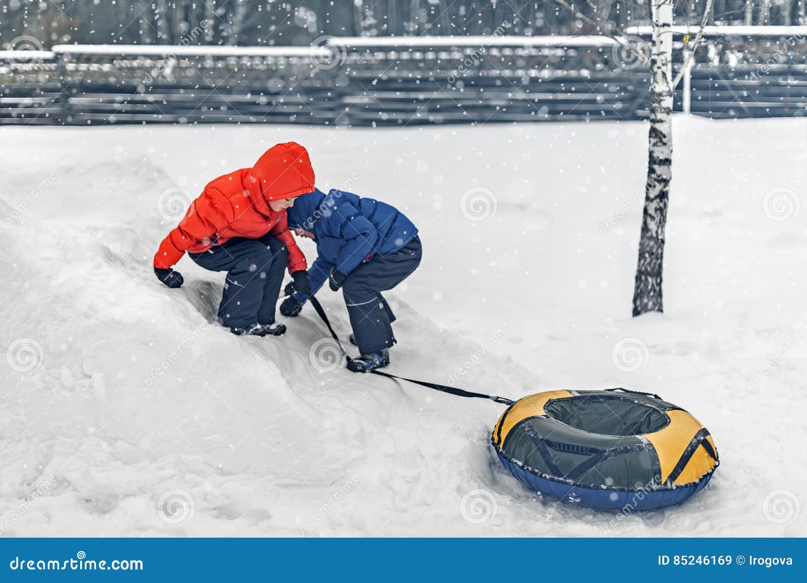 Twins Play Snowfall Time with the Inflatable Sledge, Snow Tube Stock ...