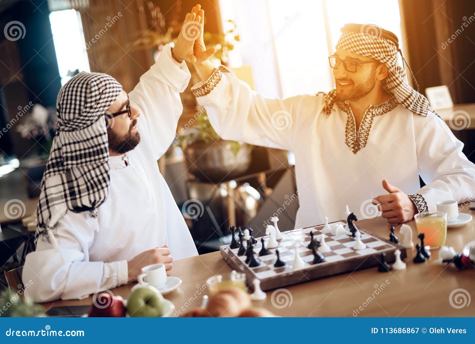 Two Arab Businessmen High Five Behind Chessboard at Hotel Room. Stock ...