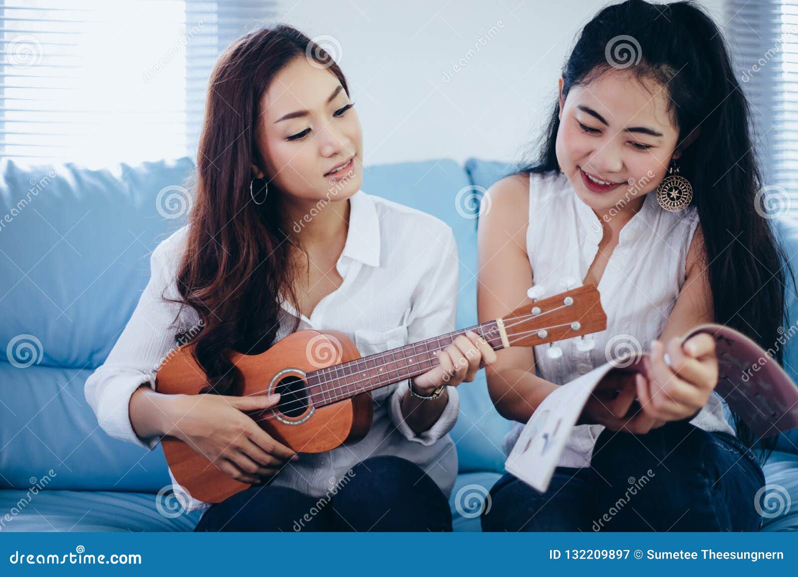 Two Asia Women Are Having Fun Playing Ukulele And Smiling At Ho Stock