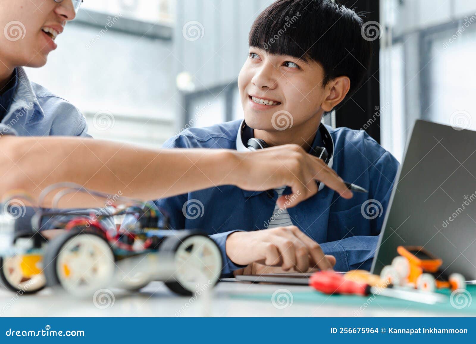 Two Asian Teenagers Constructing Robot Arm Project with Laptop in ...