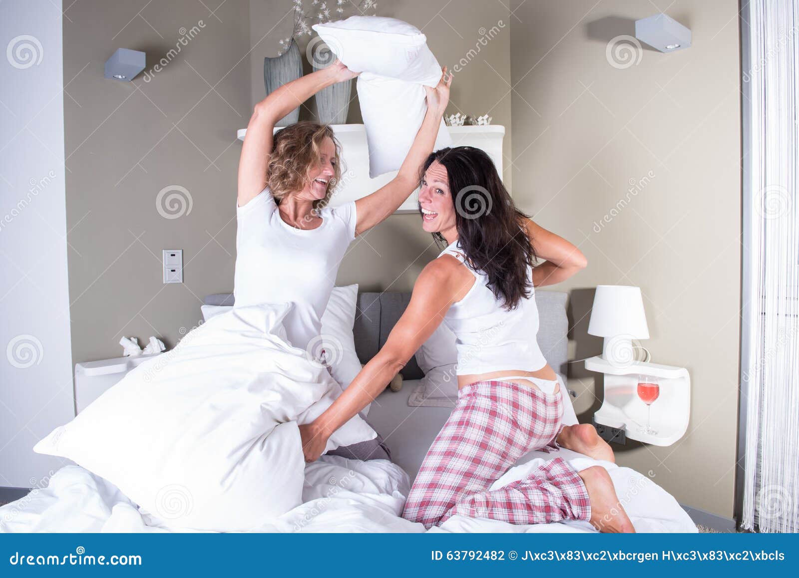 Two Attractive Women Having a Pillow Fight in Bed Stock Photo - Image ...