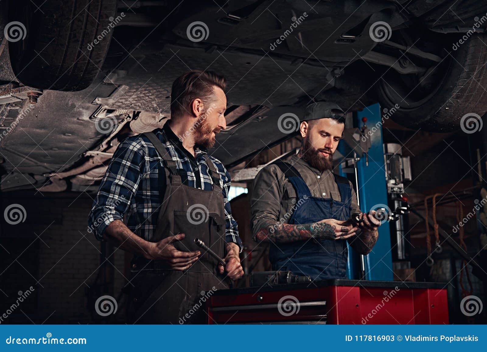 Two Auto Mechanic in a Uniform, Working on a Workbench while Standing ...