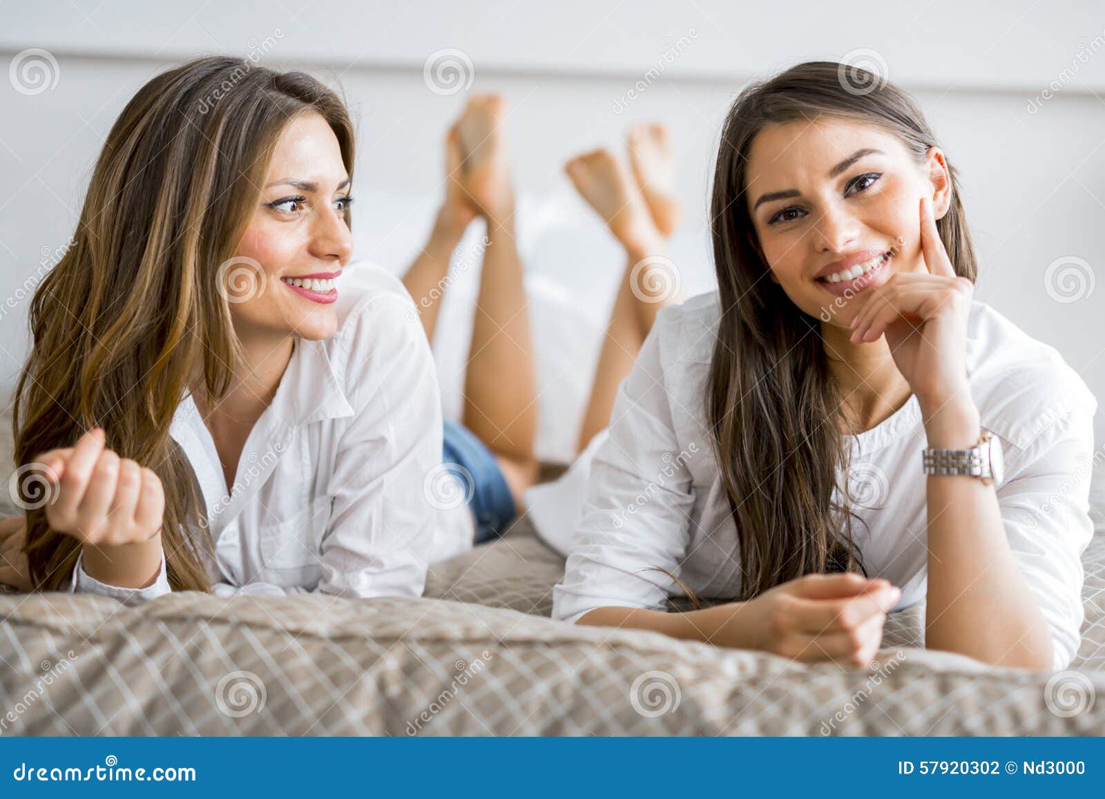 Two Beautiful Girls Talking and Smiling while Lying on a Bed Stock ...