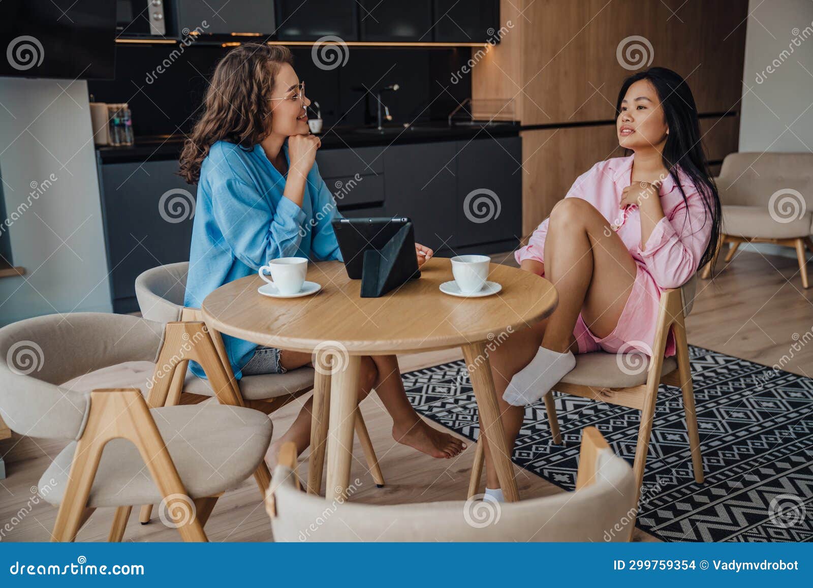 Two Beautiful Women Drinking Coffee And Talking While Sitting In