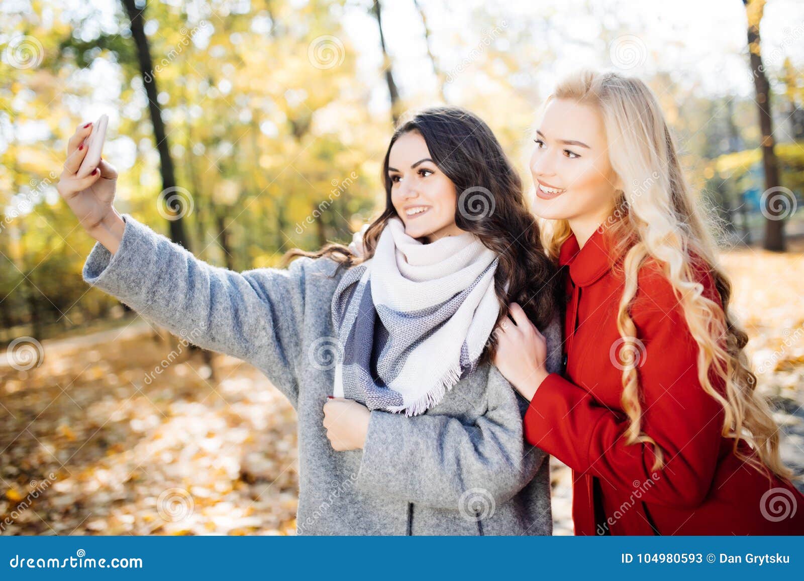 Two Beautiful Young Woman Taking Selfie In Autumn Day In Park Stock