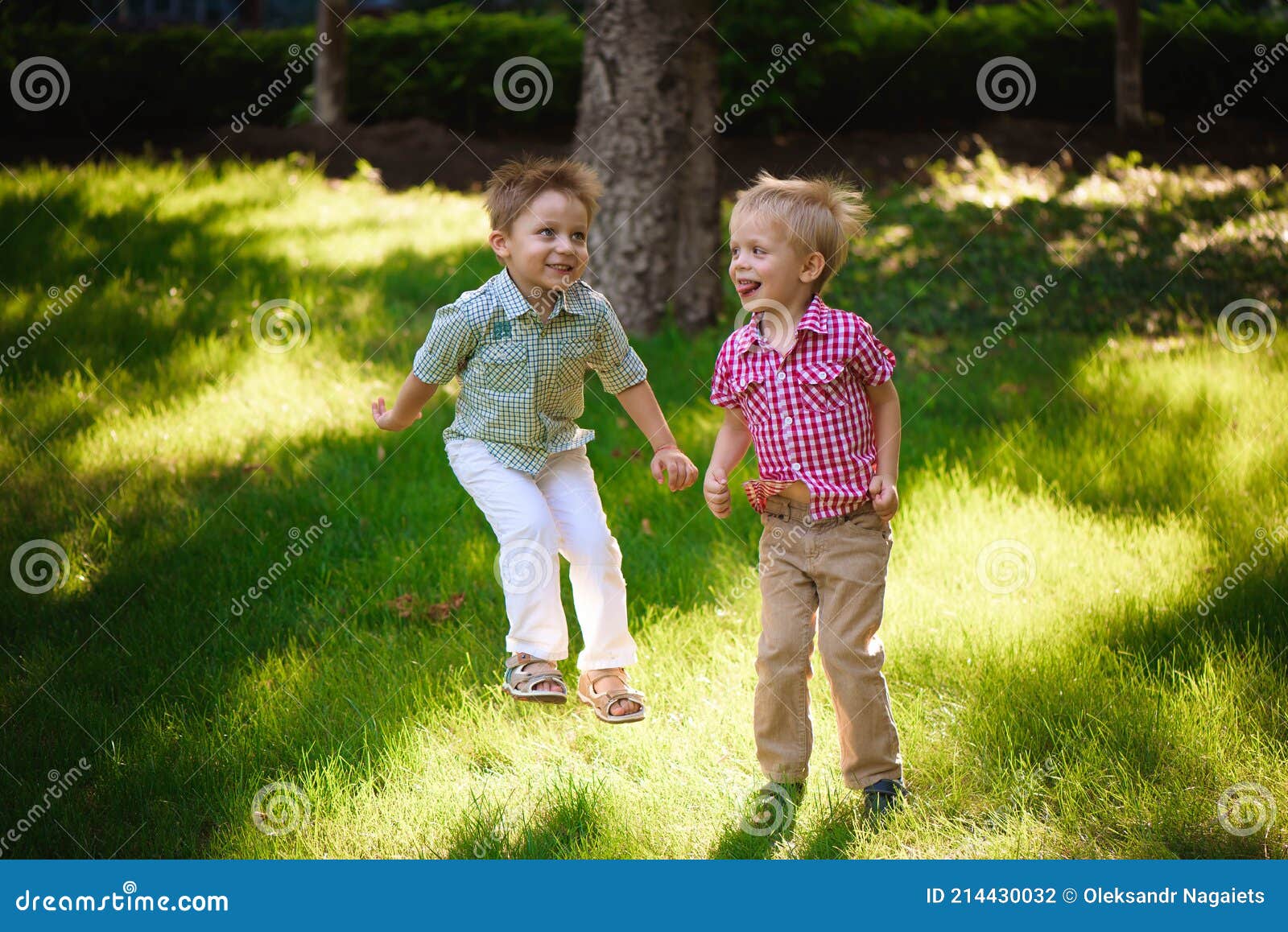 Two Boys Brothers Playing and Jumping Outdoors in a Park. Stock Photo ...