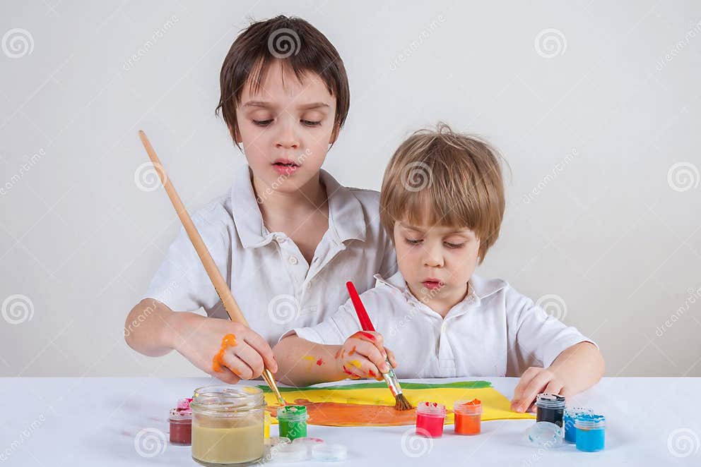 Two Boys are Drawing Together. they Paint with a Brushs at the Same ...