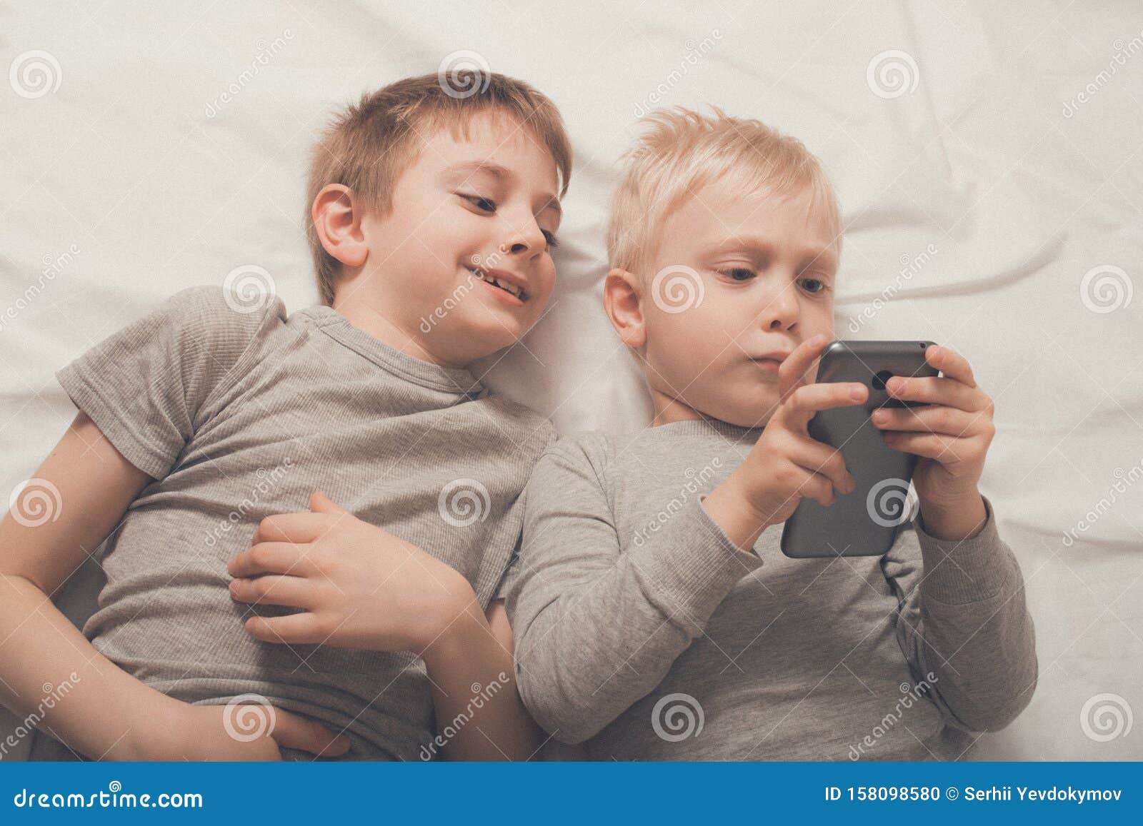Two Boys are Lying in Bed with a Smartphone. Gadget Leisure Stock Photo ...