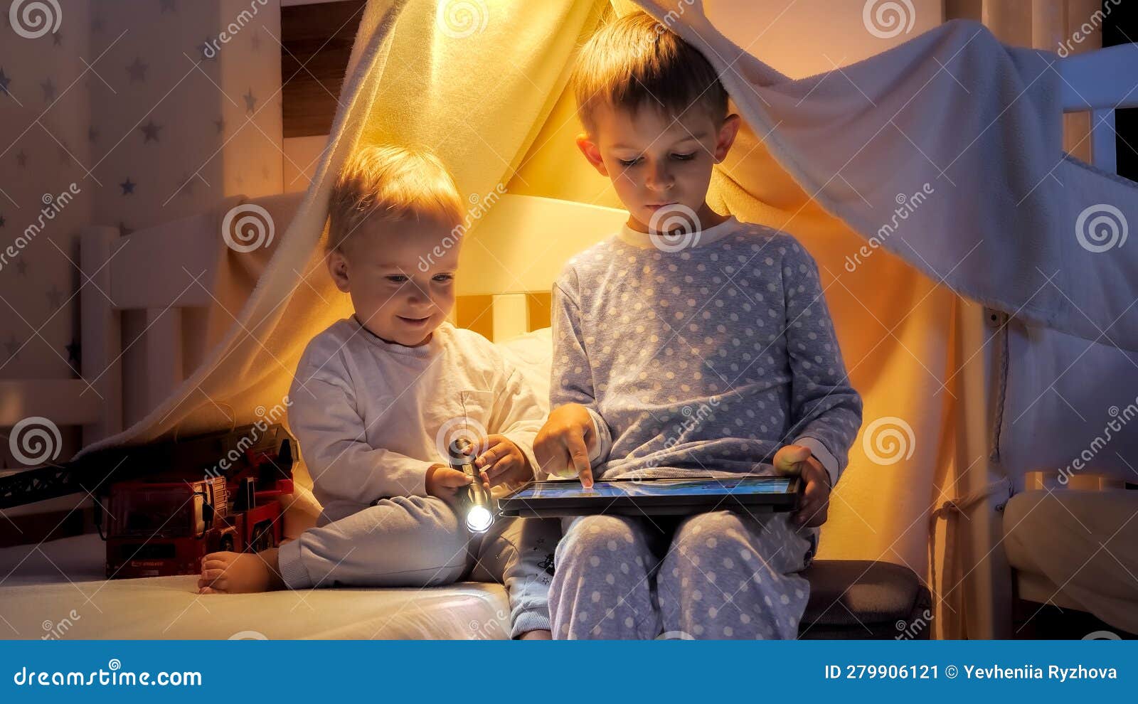 Two Boys in Pajamas Playing on Bed at Night and Using Tablet Computer ...