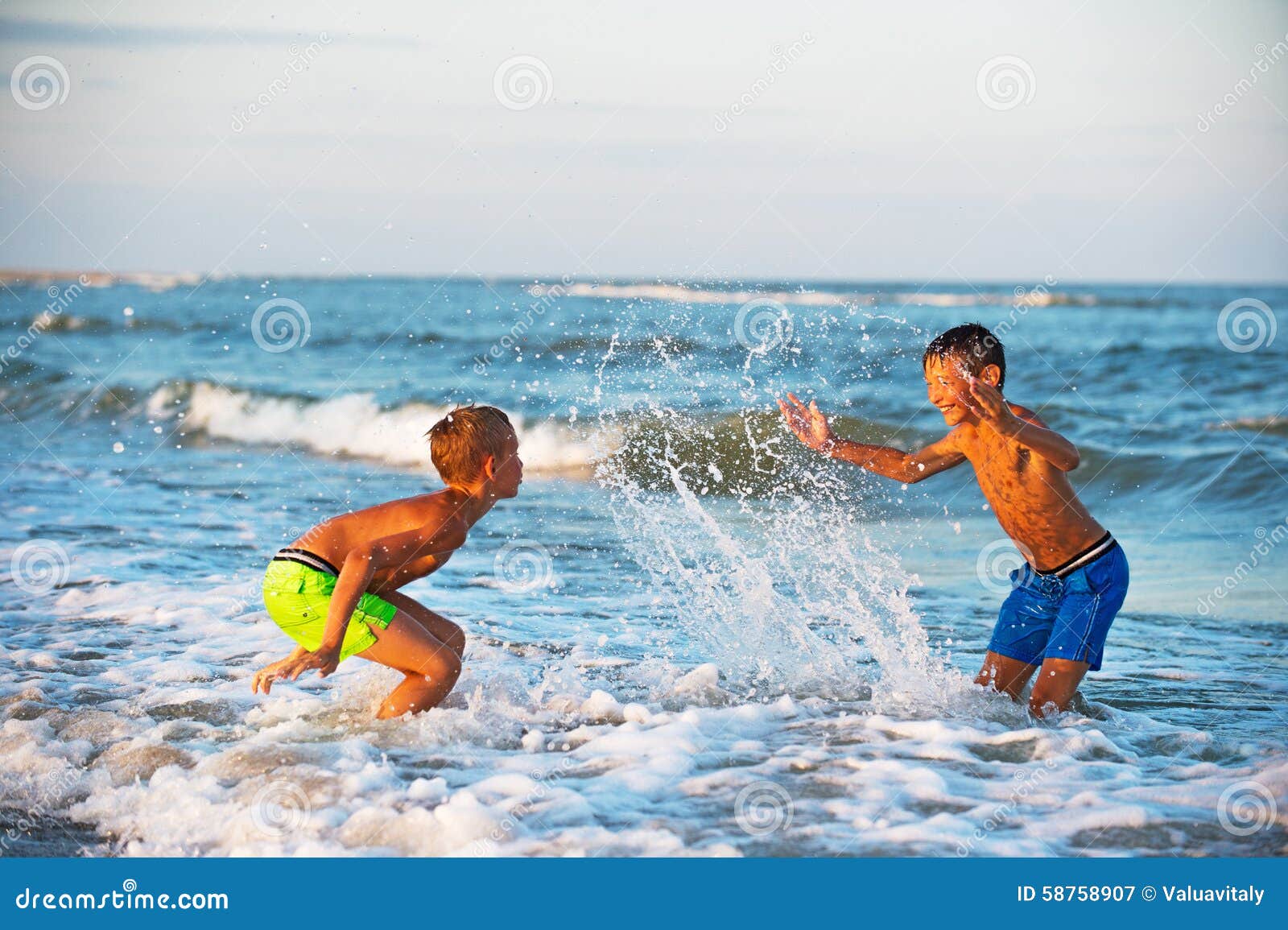 Two Boys Playing at the Beach with Water. Stock Image - Image of ...