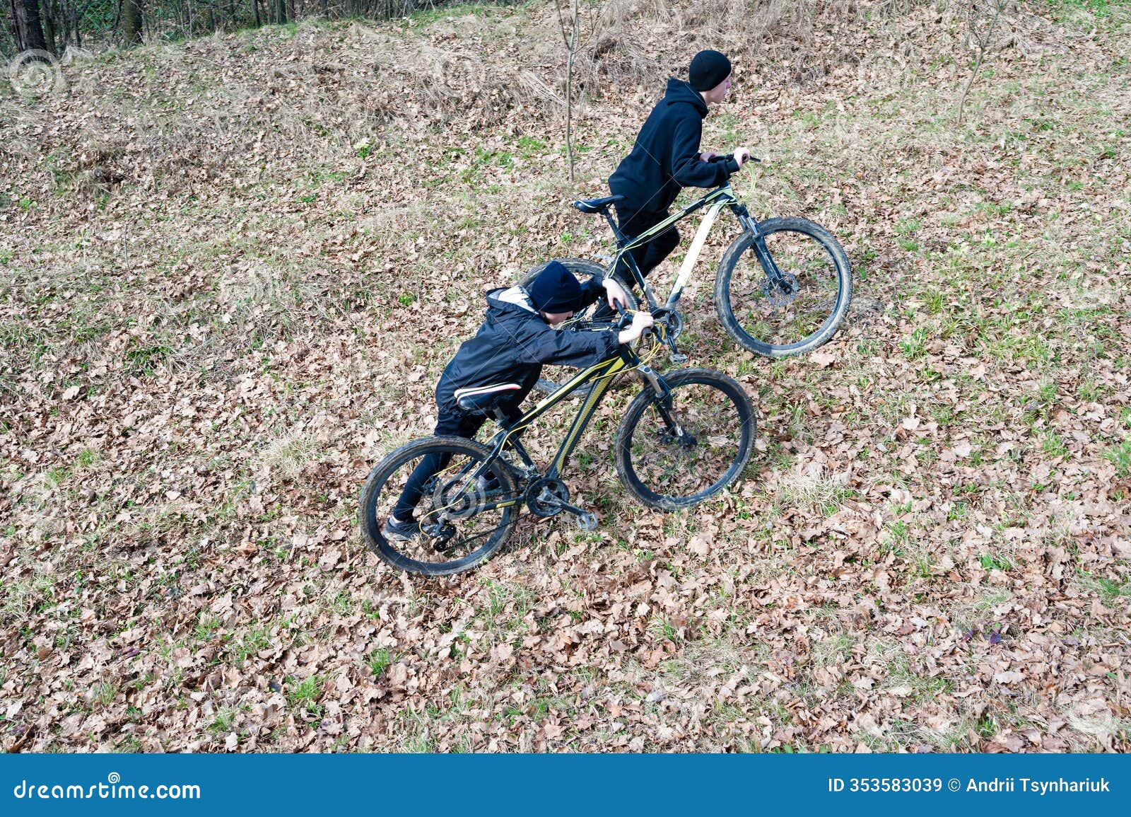 Two Boys Struggle To Push Their Mountain Bikes Uphill on a Leaf-covered ...