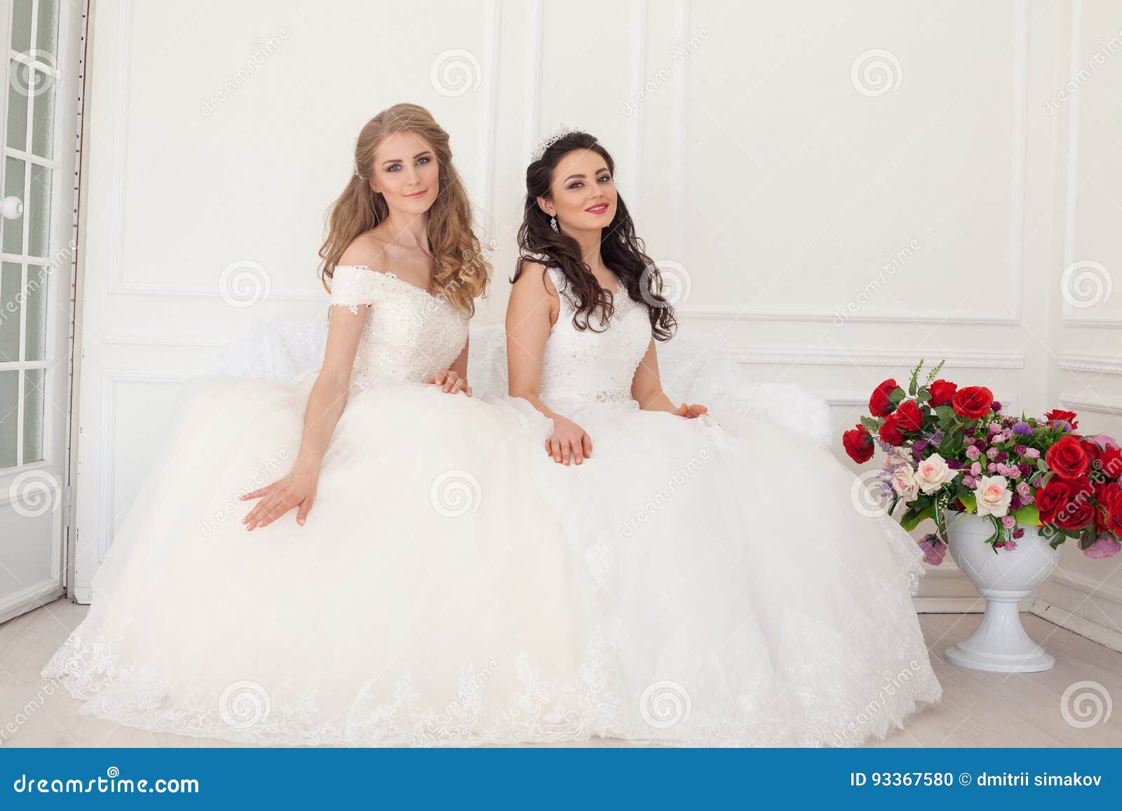 Two Brides in Wedding Dresses Sit on a White Couch Stock Photo - Image ...