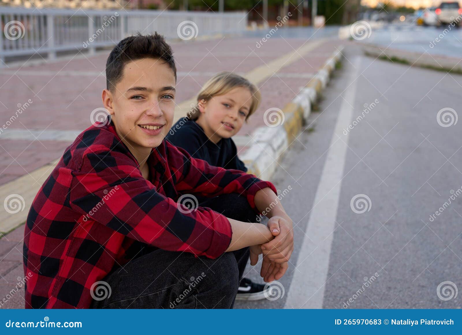 Two Brothers Sitting Outside on a Sidewalk and Have Fun. Stock Image ...