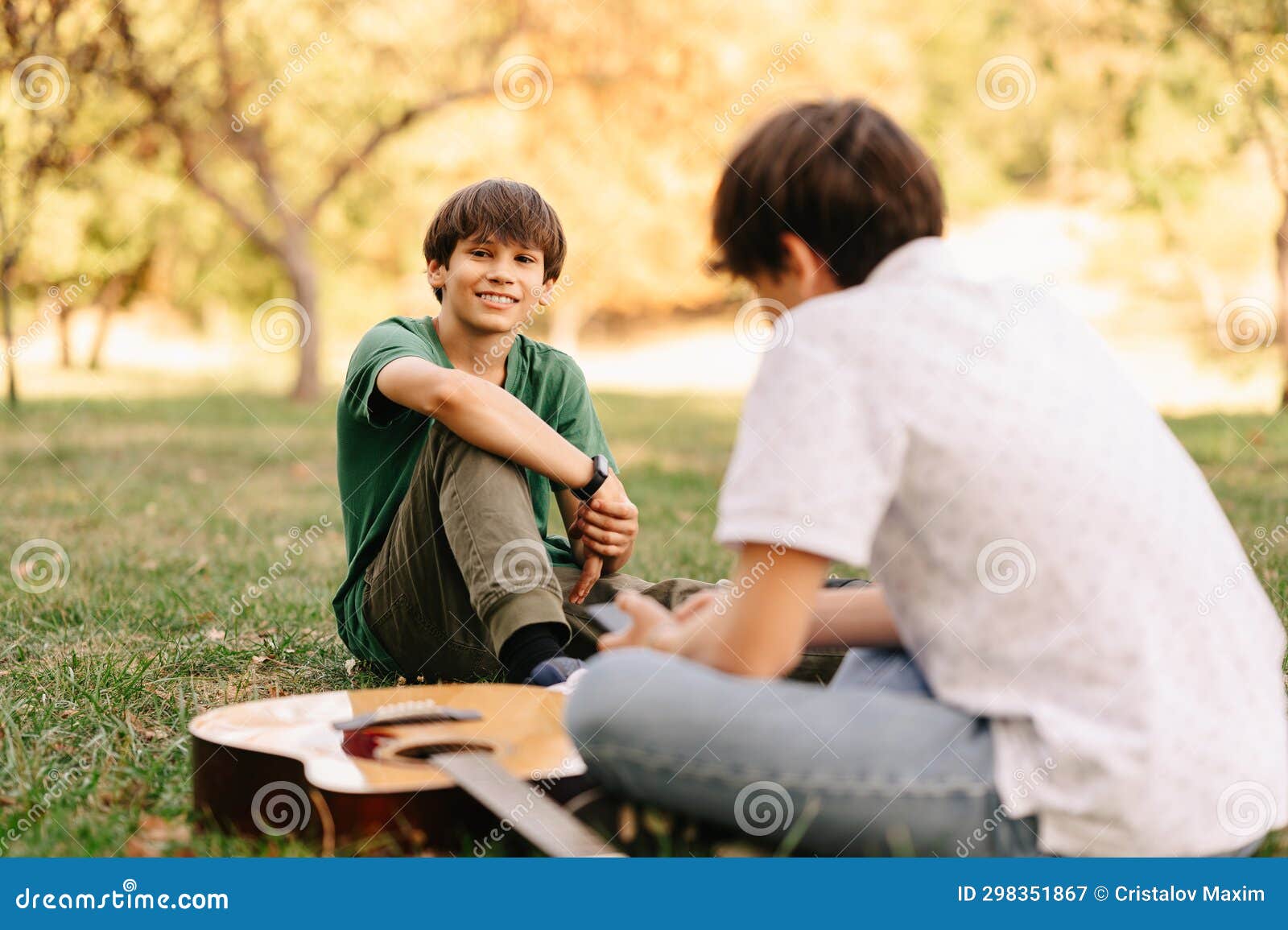 Two Brothers are Spending Time in Park while Talking and Playing Guitar ...