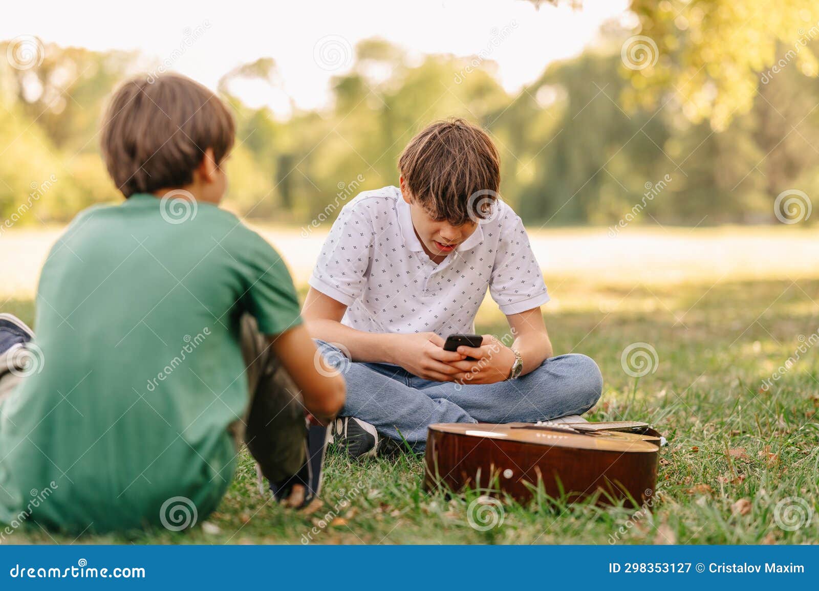Two Brothers are Spending Time in Park while Talking, Playing Phone and ...