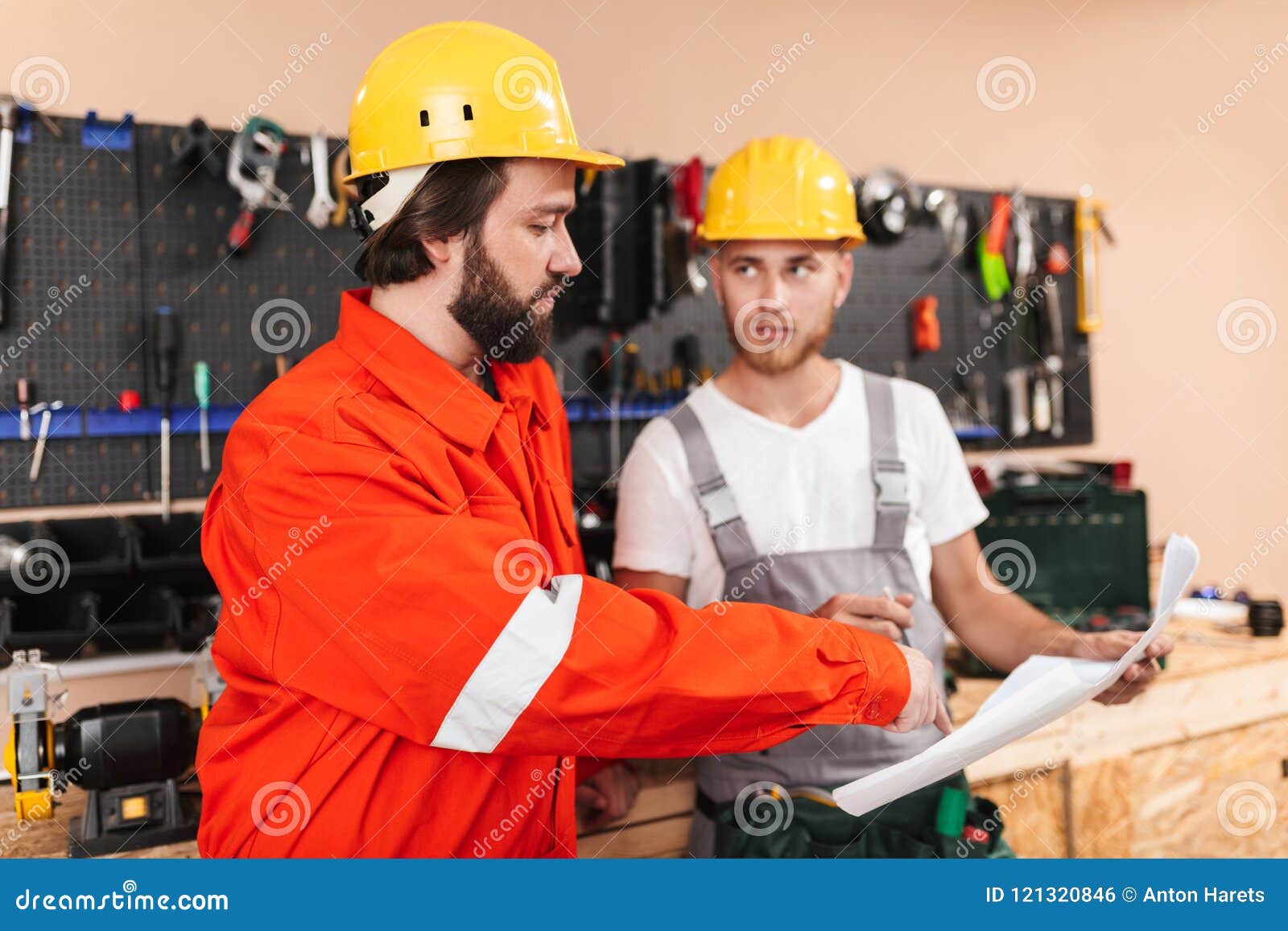Two Builders in Work Clothes and Hardhats Working in Workshop Wi Stock ...