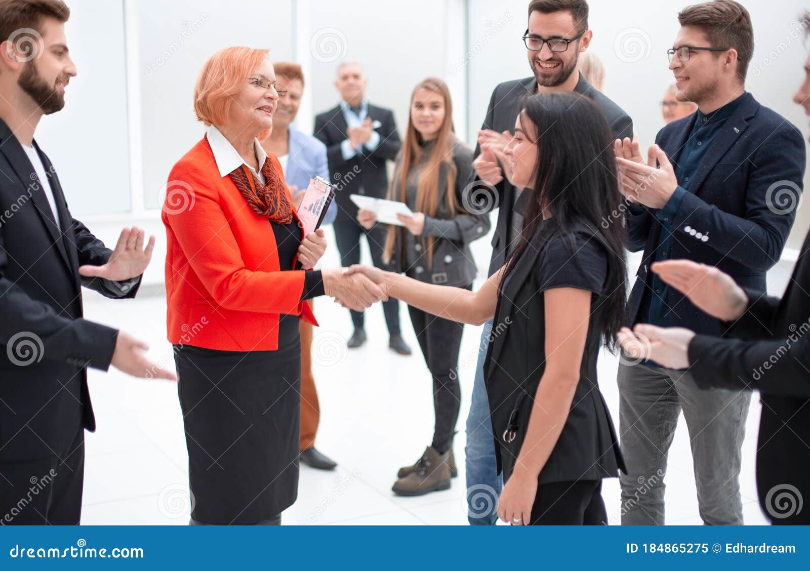 Two Business People Shaking Hands in Front of Their Colleagues Stock ...