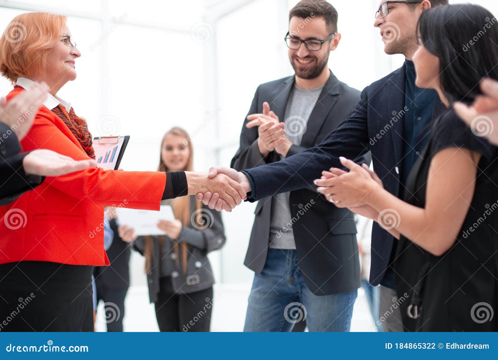 Two Business People Shaking Hands in Front of Their Colleagues Stock ...