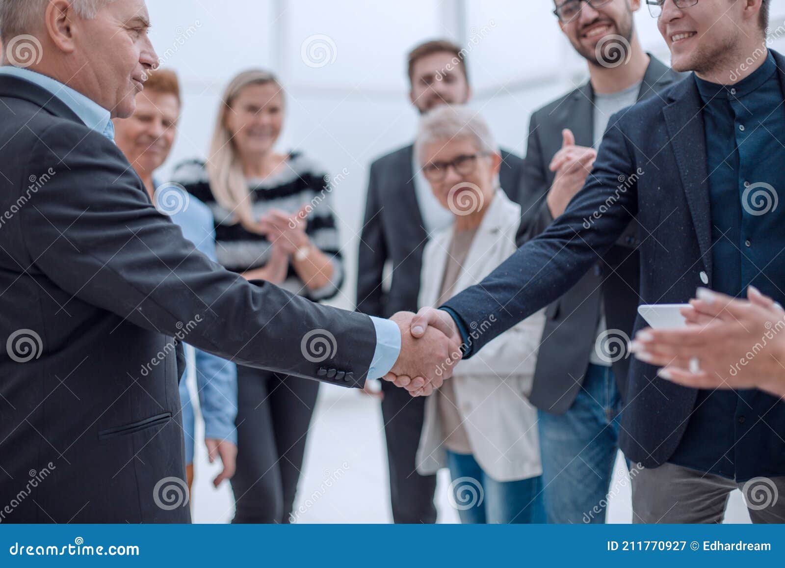 Two Business People Shaking Hands in Front of Their Colleagues Stock ...