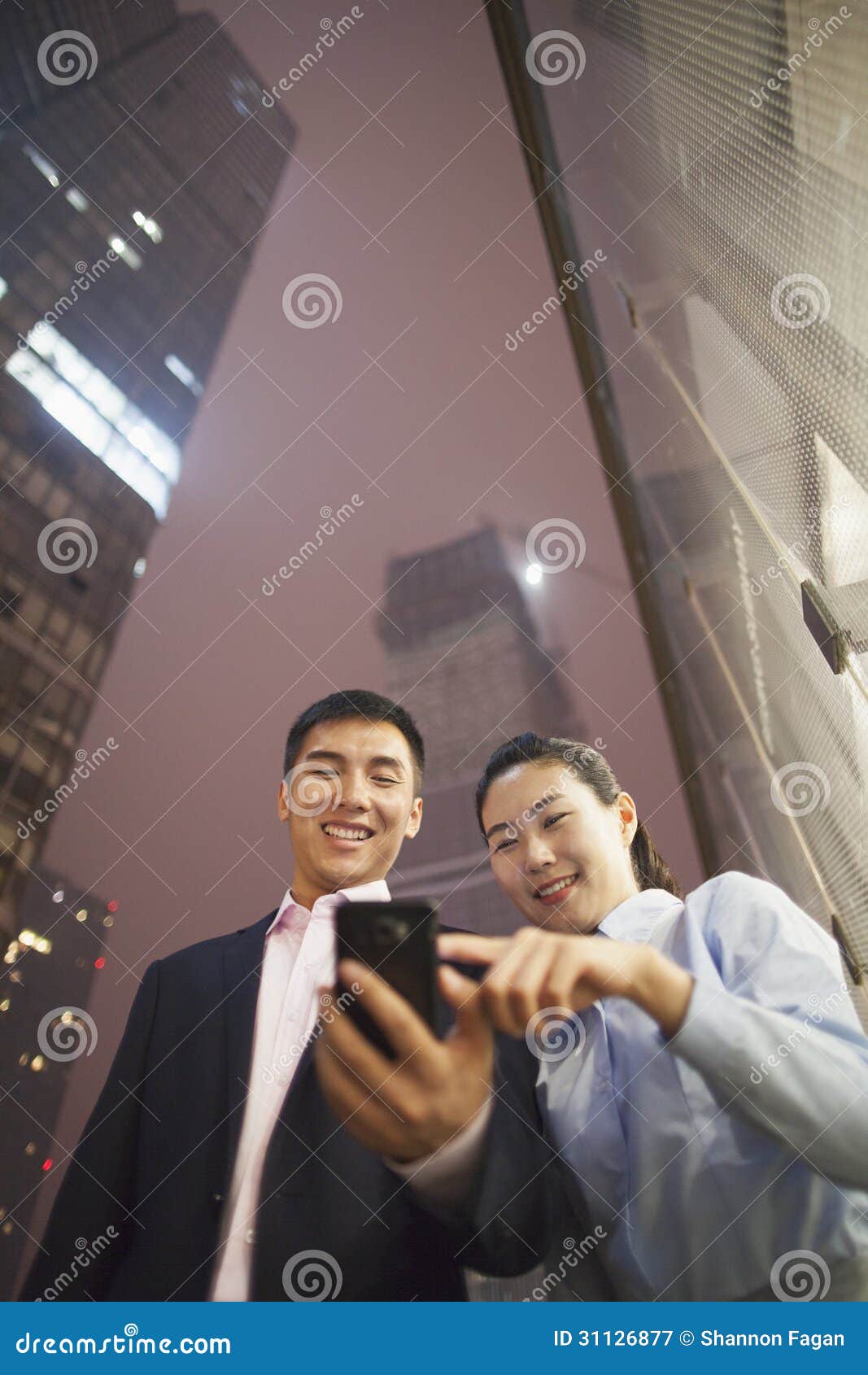 Two Business People Smiling and Looking at the Phone, Pointing ...