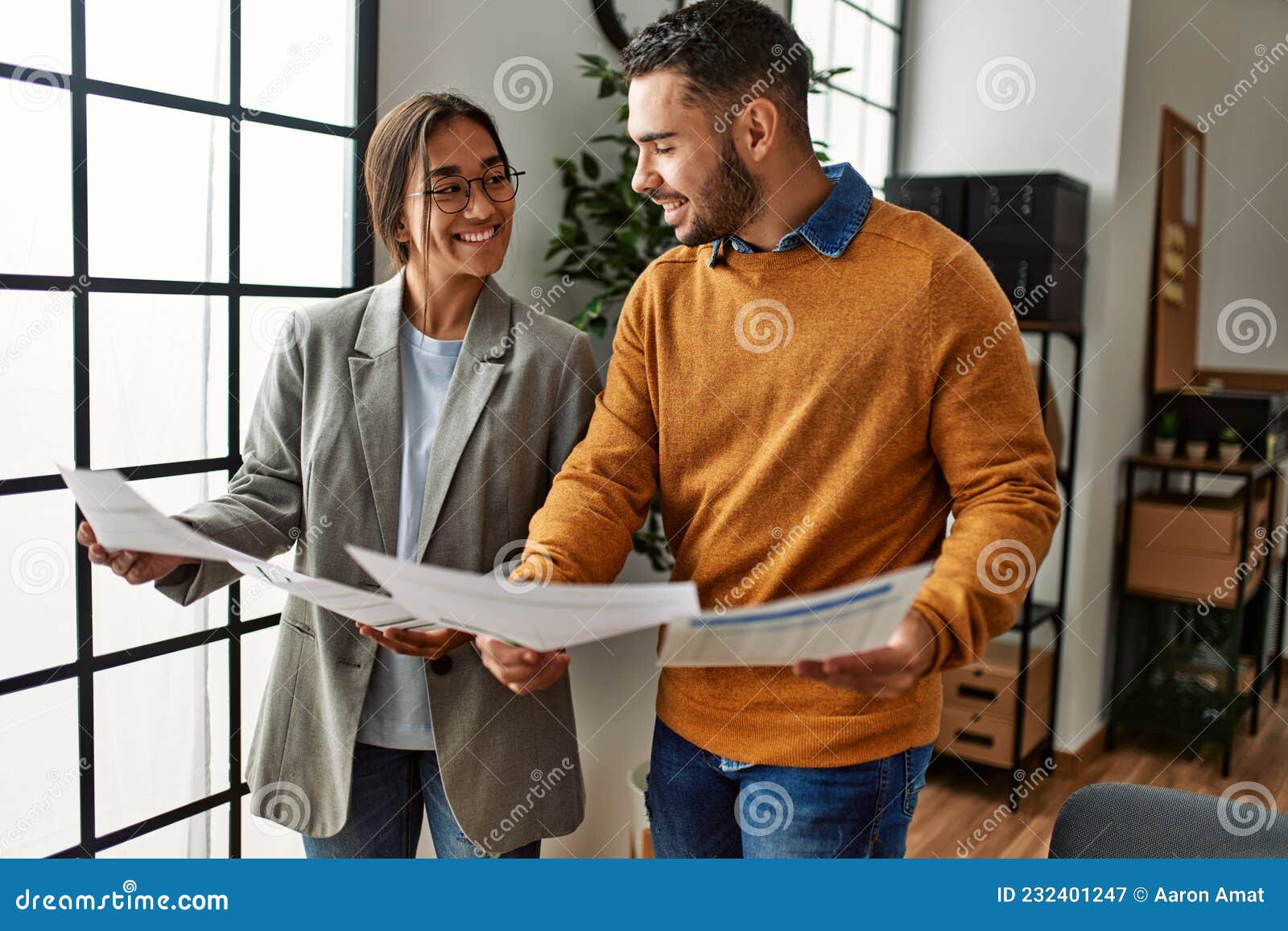 Two Business Workers Smiling Happy Reading Paperwork Standing at the ...
