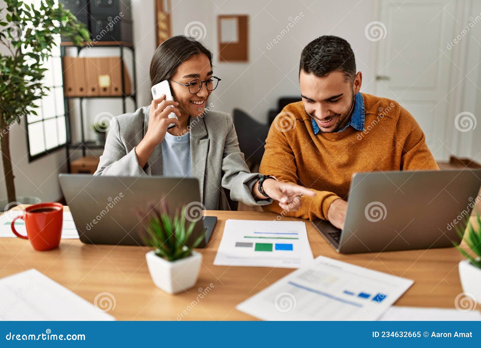 Two Business Workers Talking on the Smartphone and Using Laptop at the ...