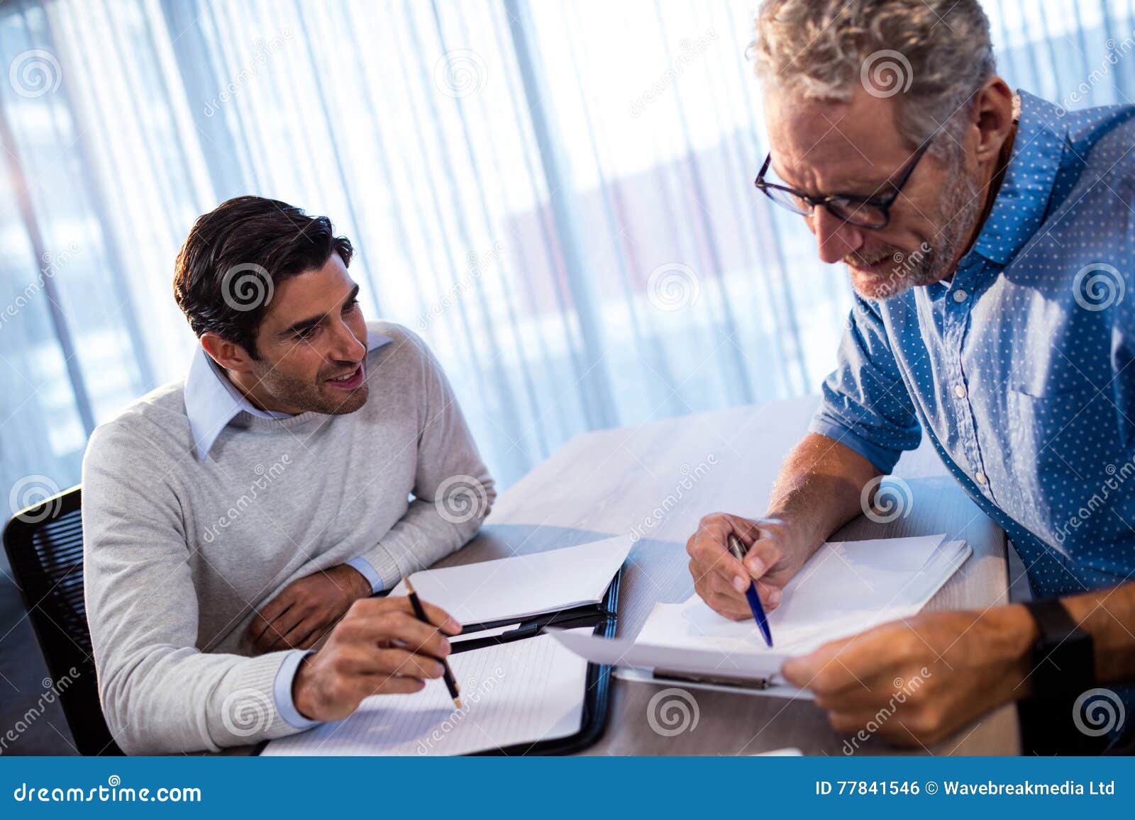 Two Businessmen Reading a Document and Interacting Stock Photo - Image ...