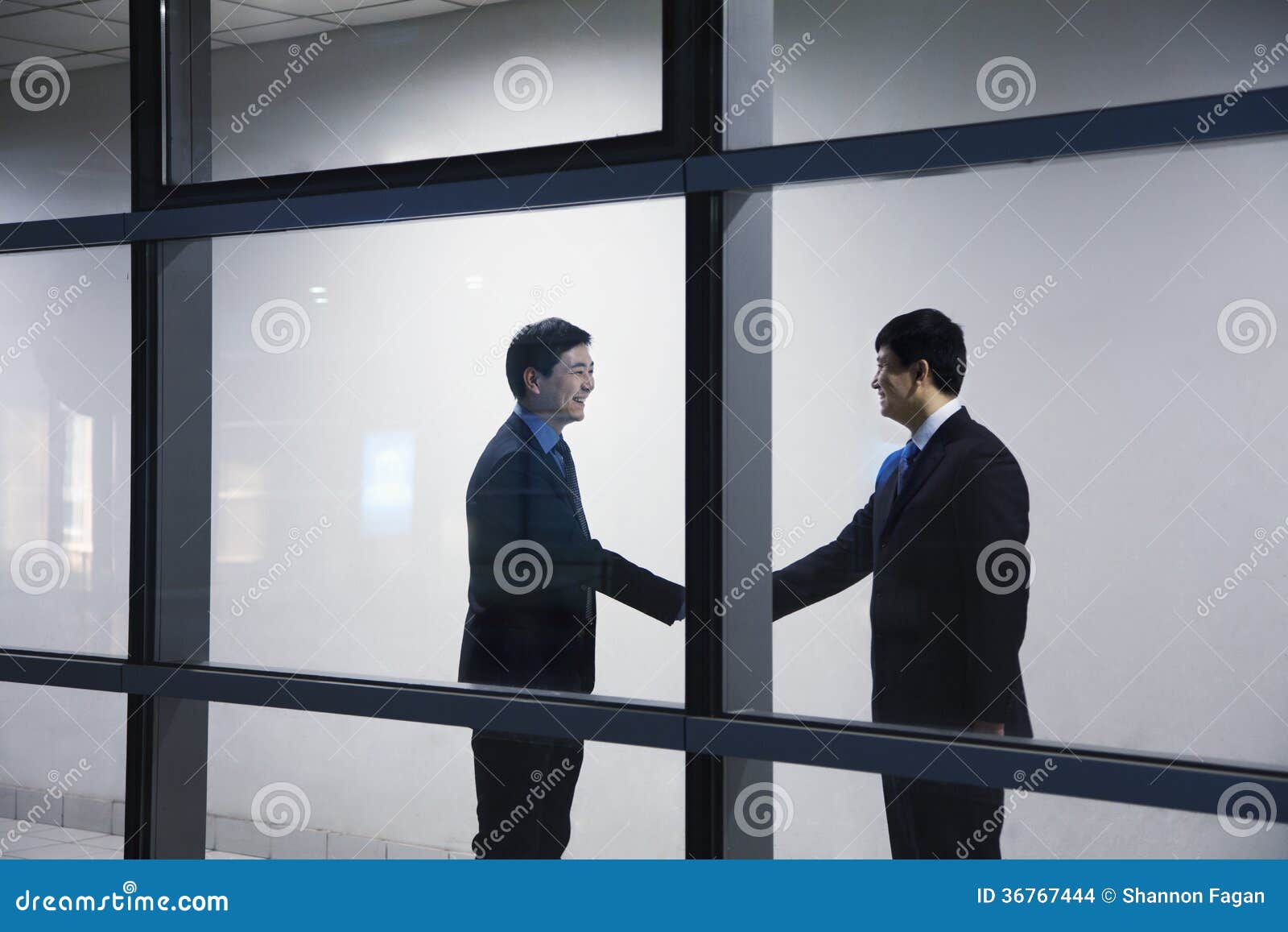 Two Businessmen Shaking Hands, Seen through Glass Wall Stock Photo ...