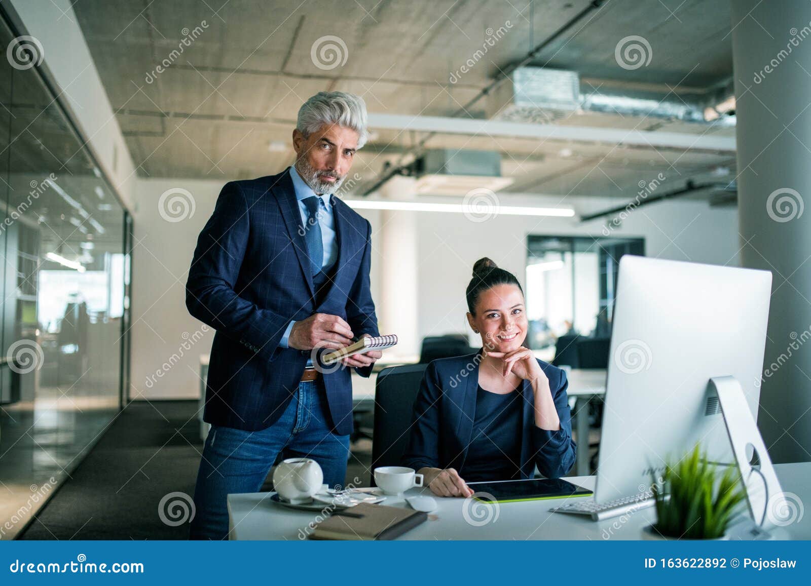 Two Businesspeople with Computer Sitting in an Office at Desk. Stock ...