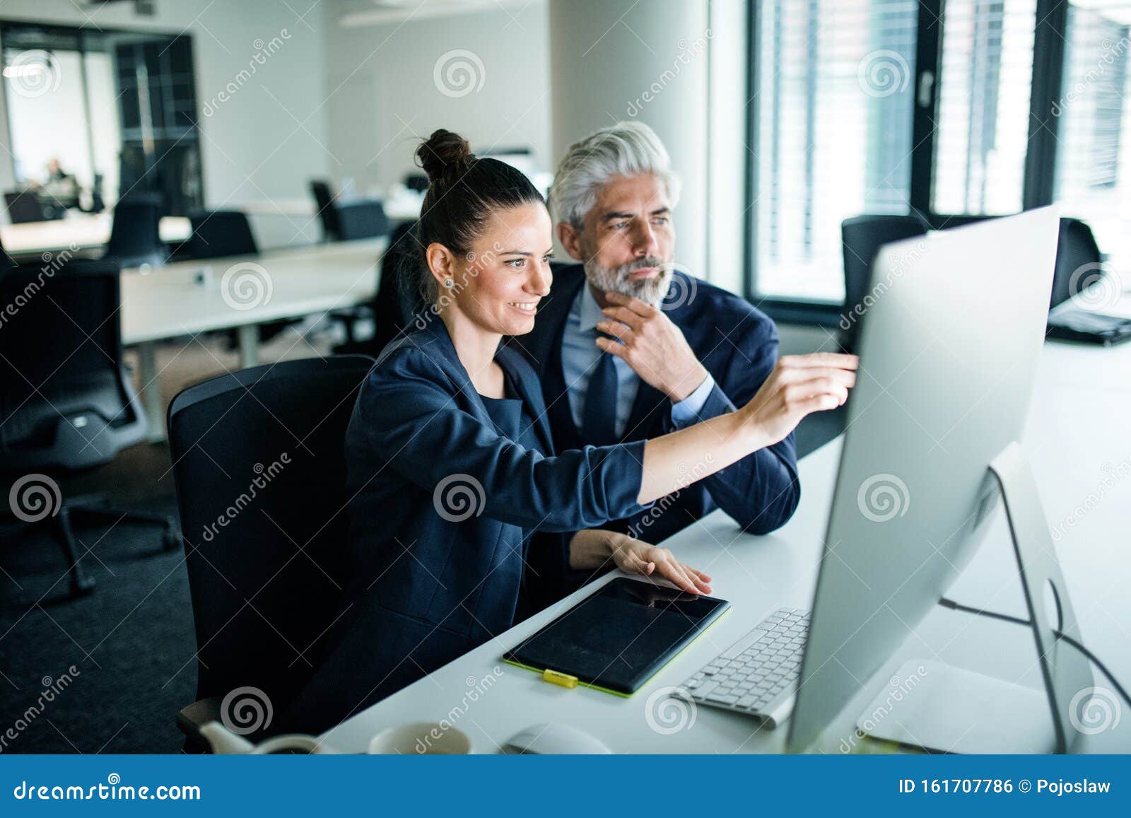 Two Businesspeople with Computer Sitting in an Office at Desk. Stock ...