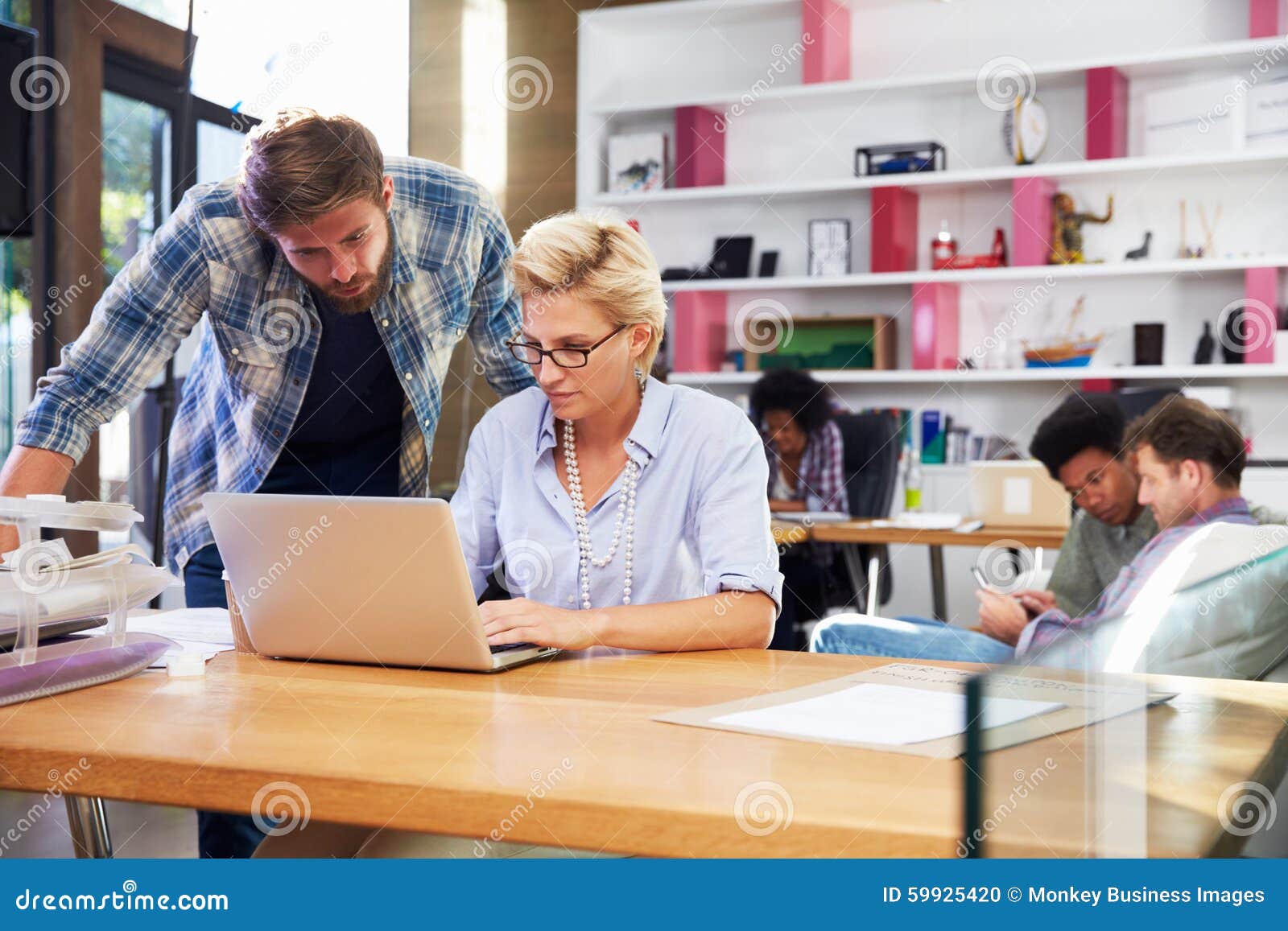 Two Businesspeople Working on Laptop in Busy Office Stock Photo - Image ...