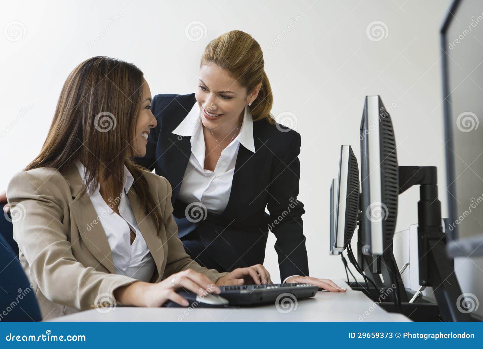 Two Businesswomen Smiling Over Computers on Table Stock Image - Image ...