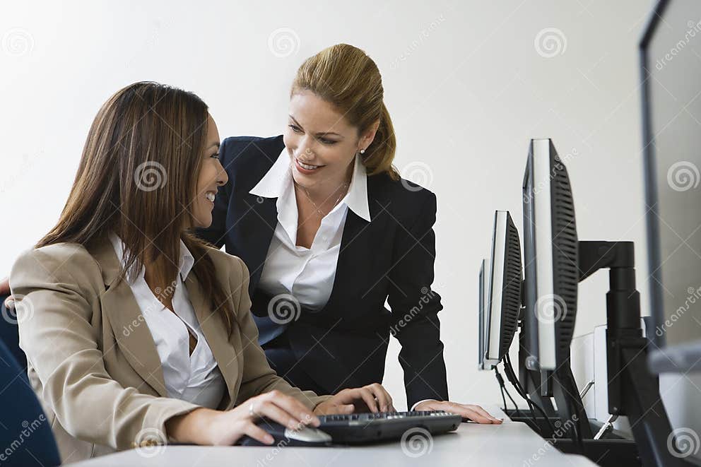 Two Businesswomen Smiling Over Computers on Table Stock Image - Image ...